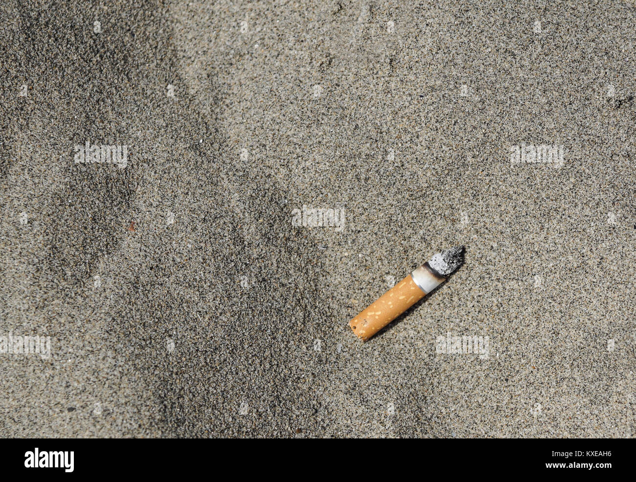 Cigarette on sand beach pollution rubbish Stock Photo - Alamy