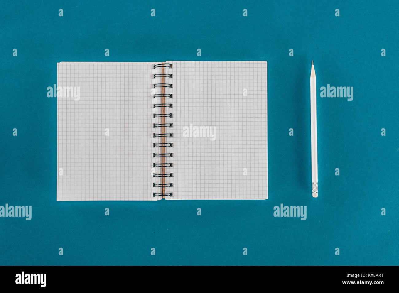 Top view of single pencil with blank notebook isolated on blue ...