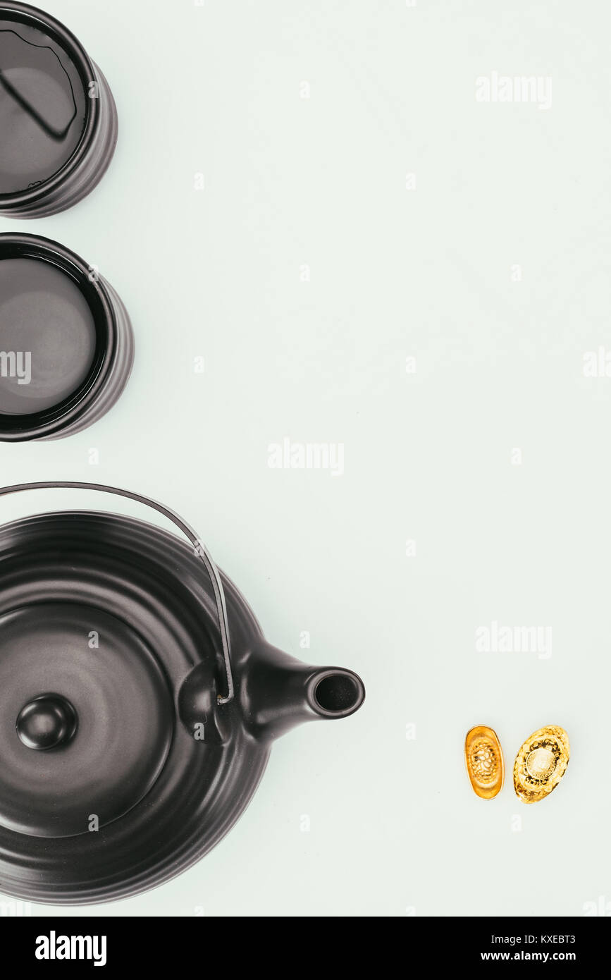 top view of chinese teapot with mugs and gold ingots isolated on white ...
