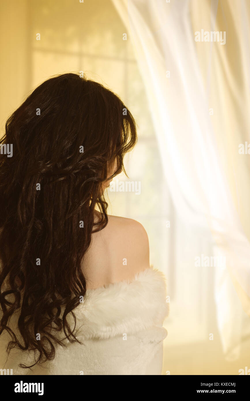 Woman in fur wrap in seductive pose agains a window with billowing ...
