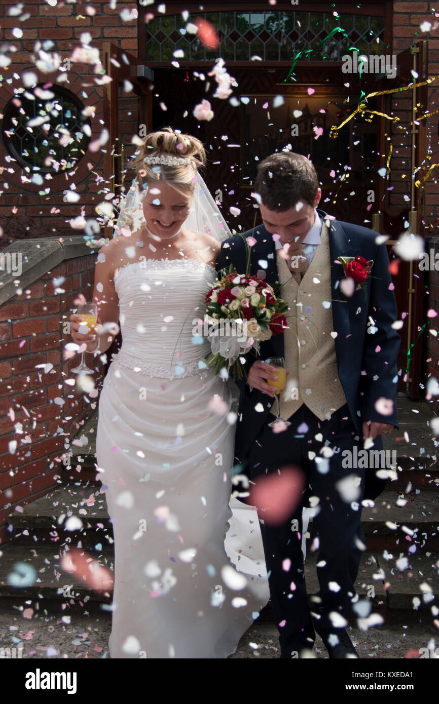 Happy, smiling bride and groom leave church as confetti is thrown after ...