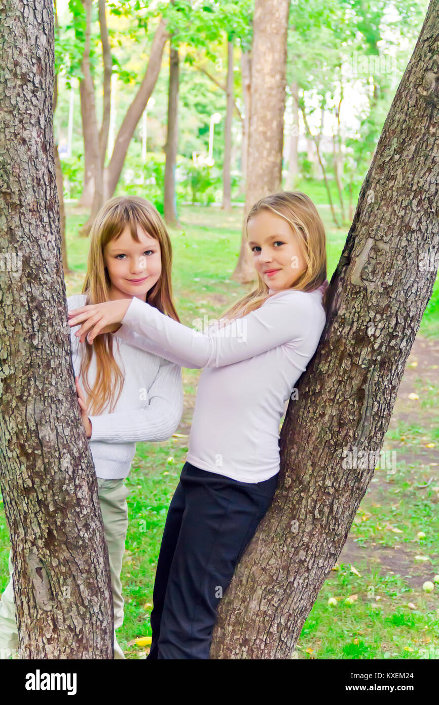 Photo of cute girls in summer sit on tree Stock Photo - Alamy
