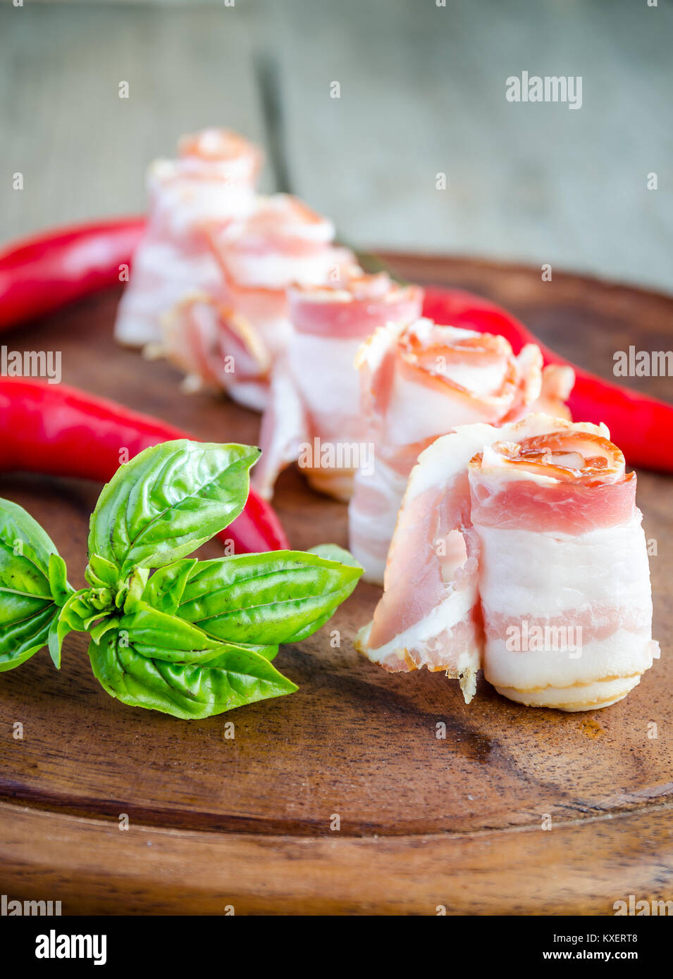 Rolled bacon strips on wooden board Stock Photo - Alamy