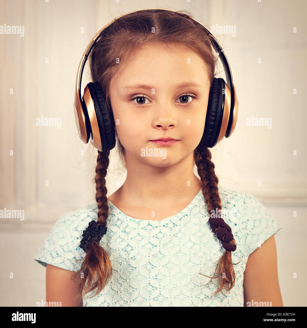Happy calm serious kid girl in blue dress listening the music in ...
