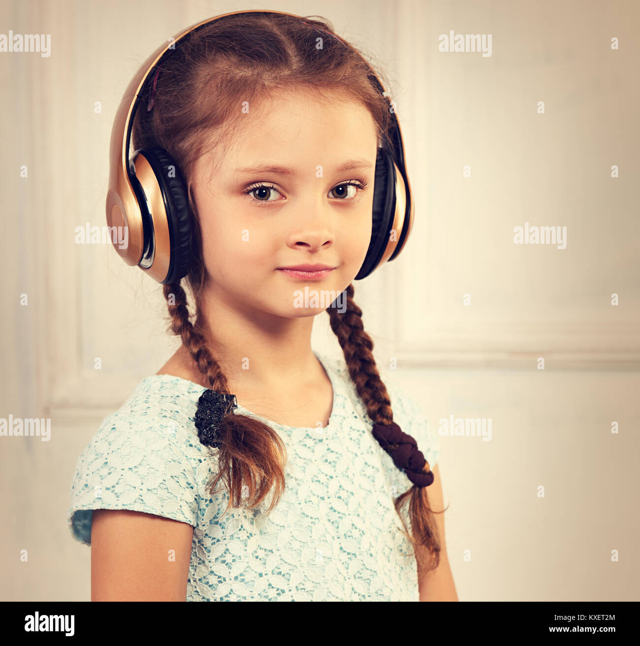 Happy calm kid girl in blue dress listening the music in wireless ...