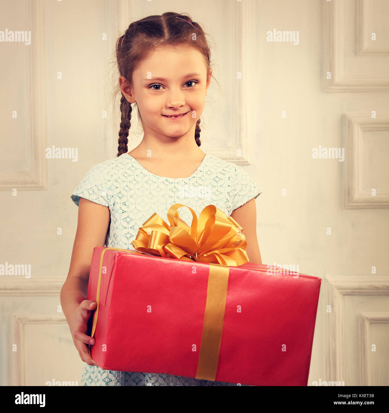 Beautiful cute kid girl holding big present box with red ribbon bow and ...