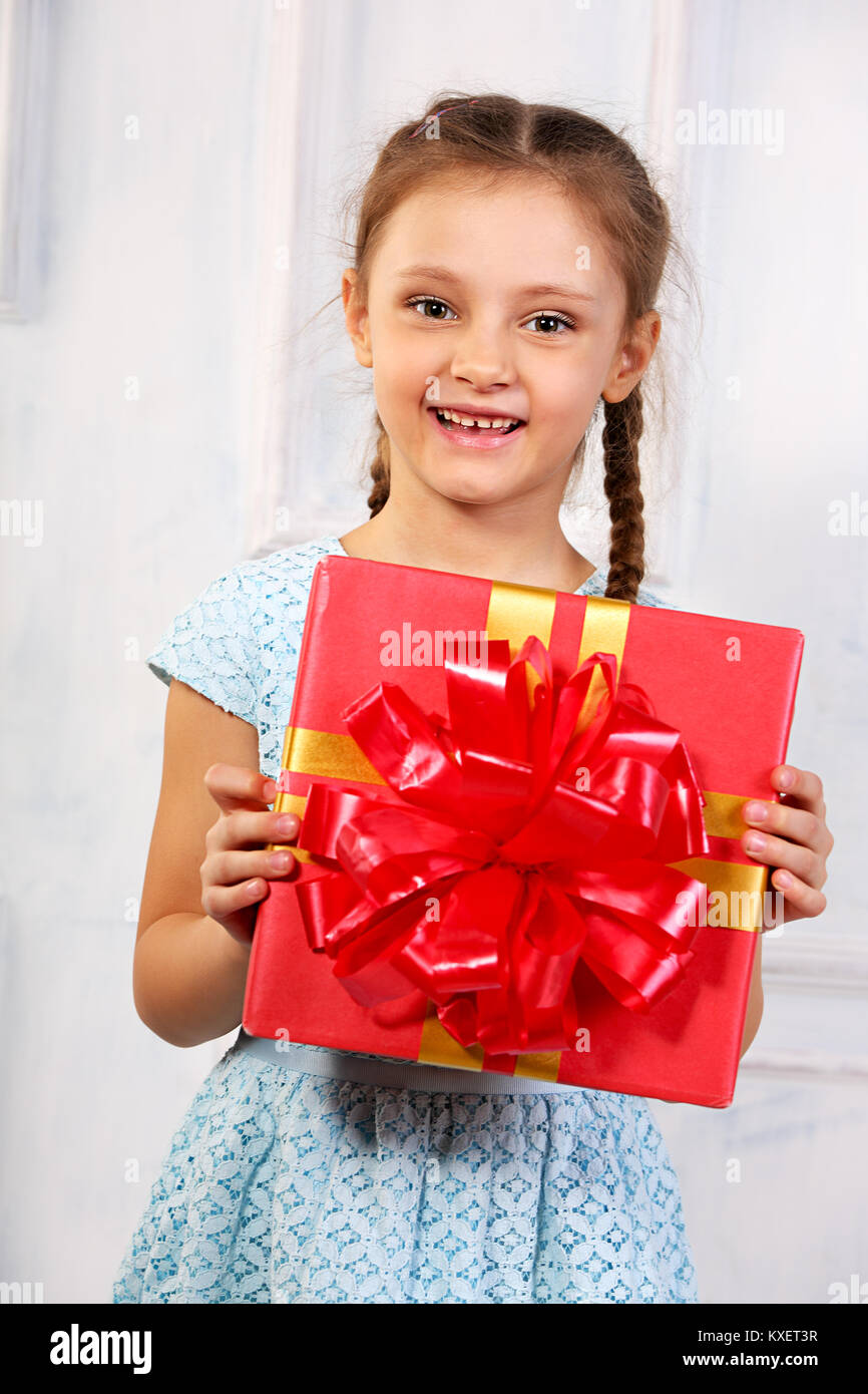 Beautiful cute kid girl holding present box with red ribbon bow and ...