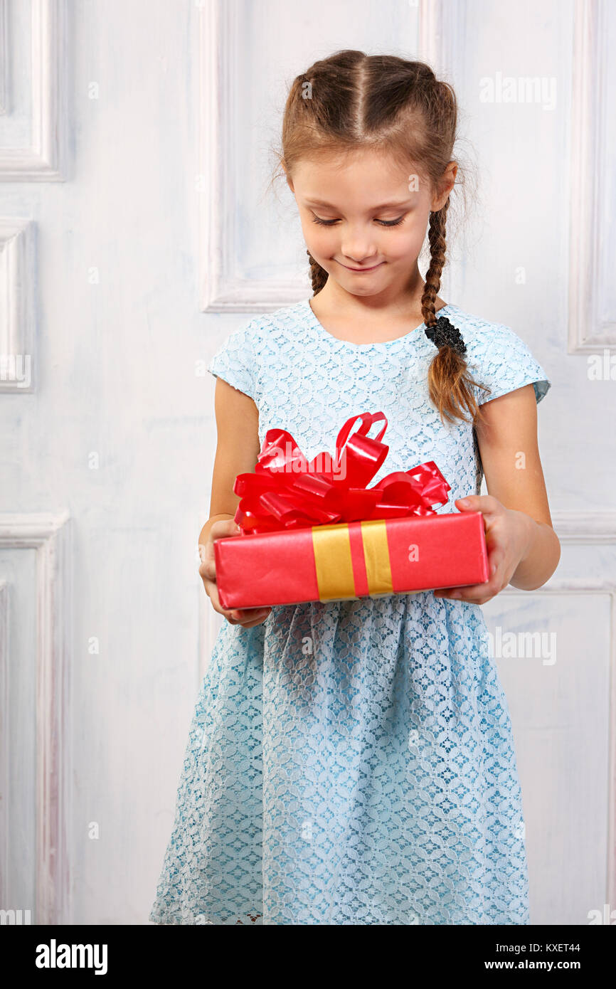 Beautiful cute kid girl holding present box with red ribbon bow and ...