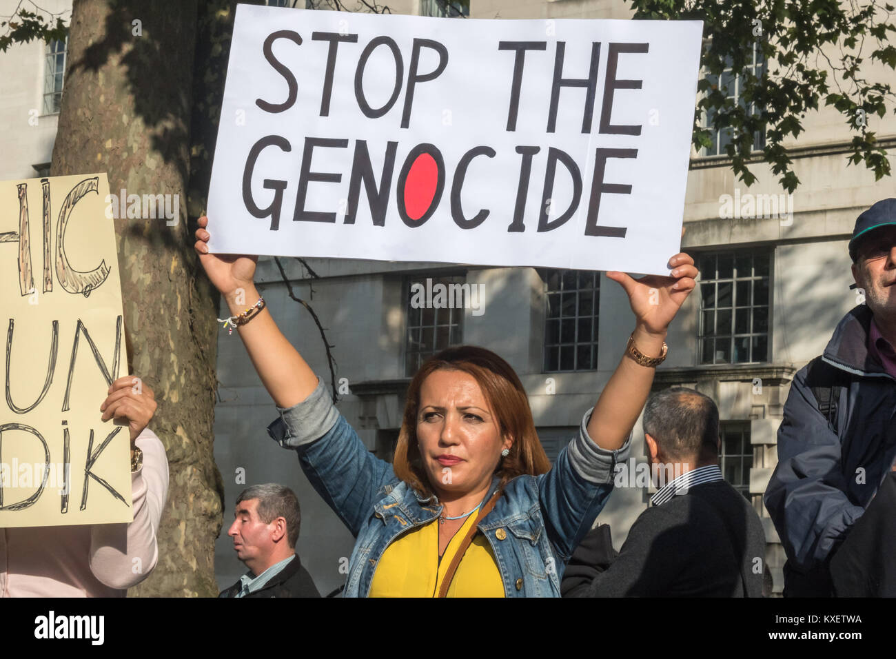 A woman holds up a poster 'Stop the Genocide' at protest by Turks and ...