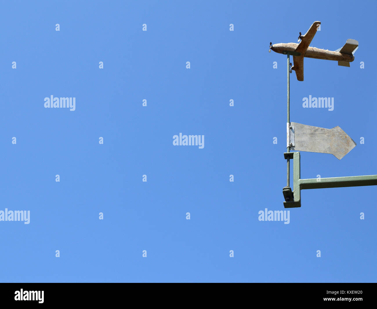 Hand made weather vane with an arrow, small plane and clear blue sky ...