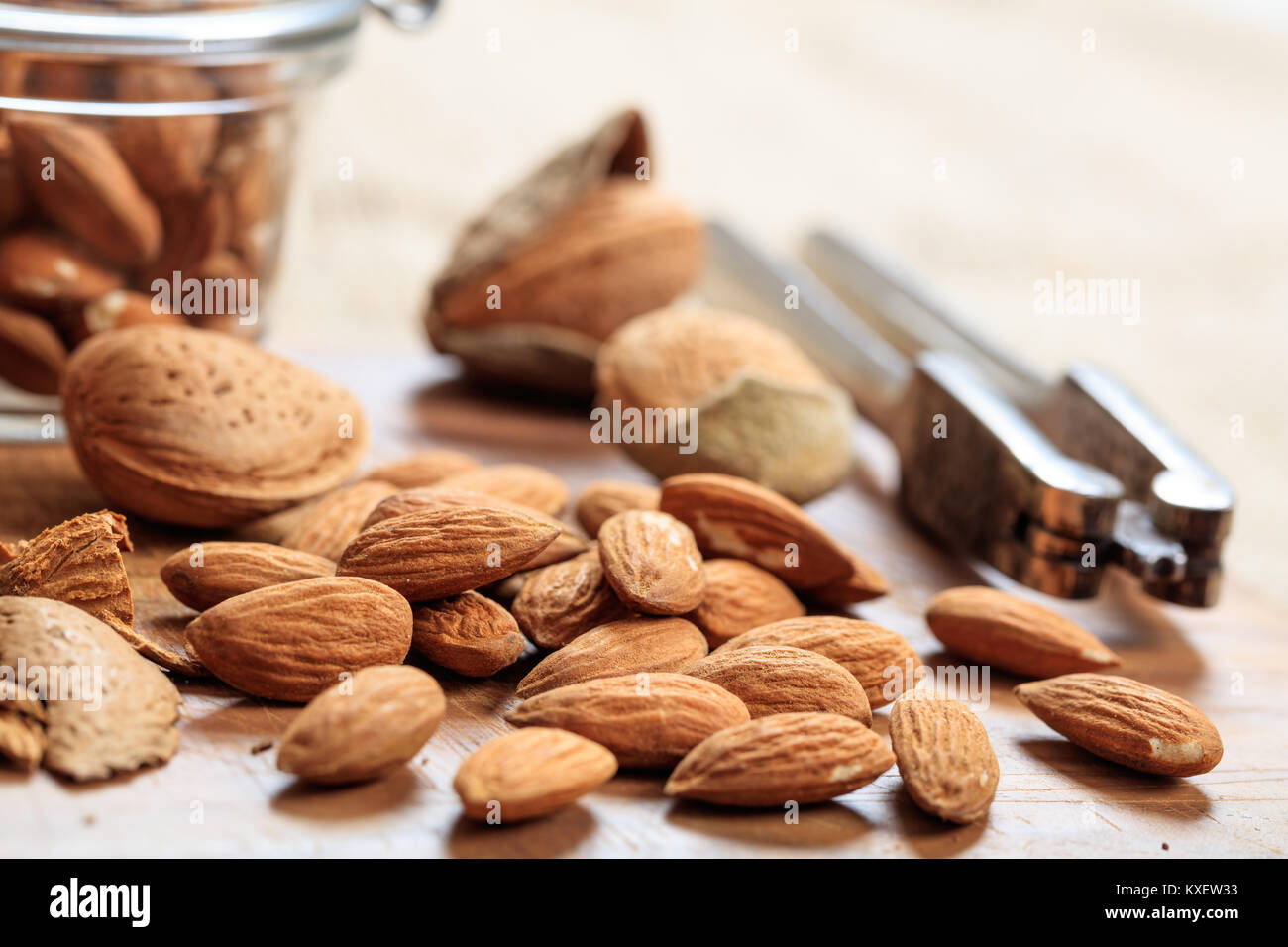 Almonds and a nutcracker on a wooden table Stock Photo - Alamy