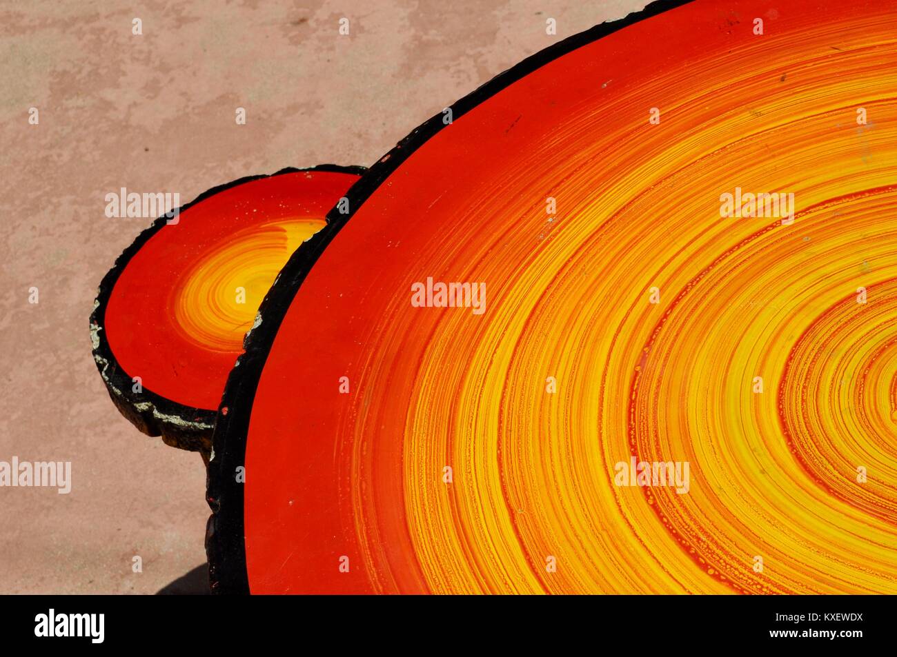 Multi-coloured red and orange table and seat made out of tree sections ...