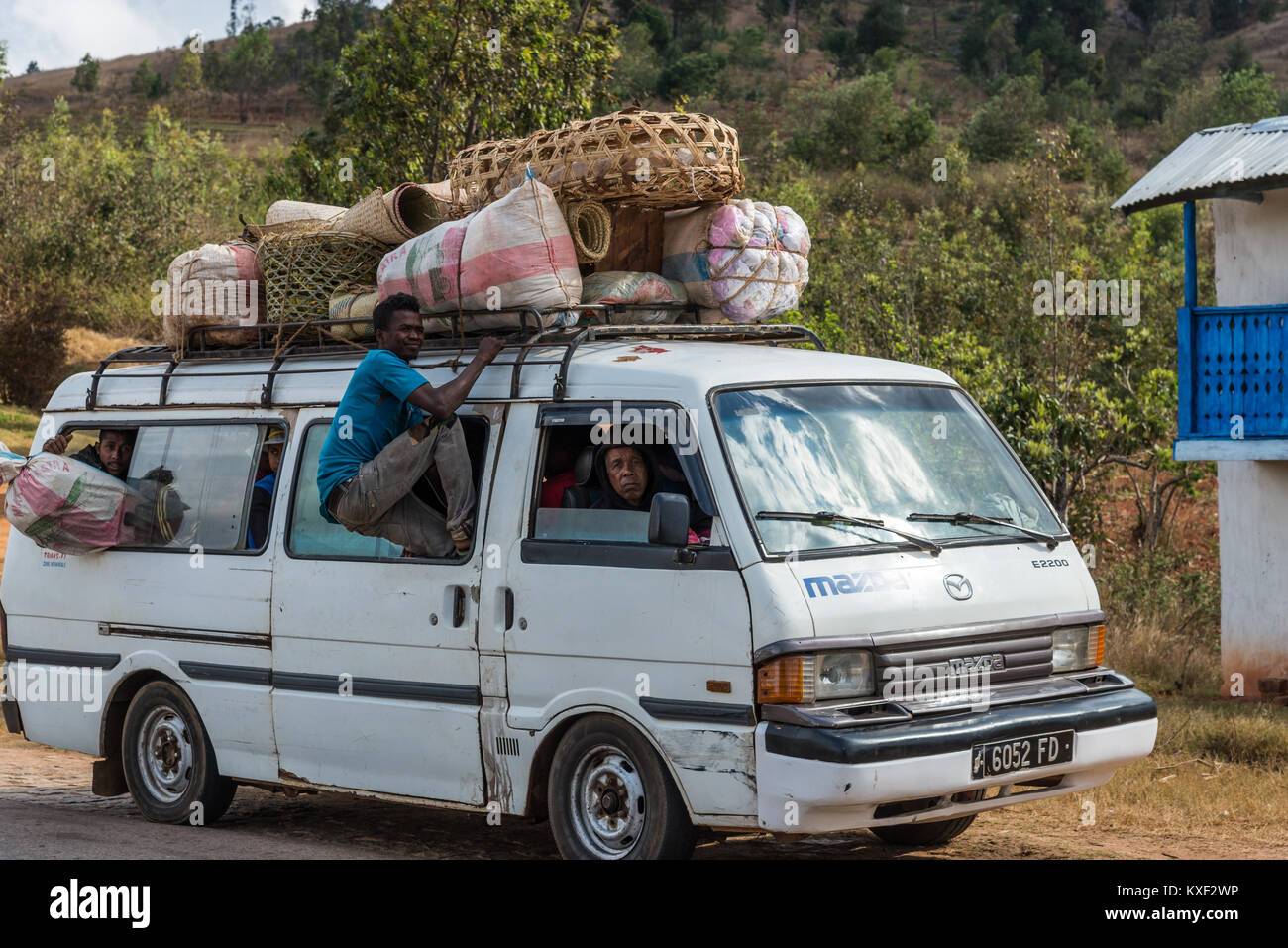 A minibus jam packed with local people and loaded with goods on top ...