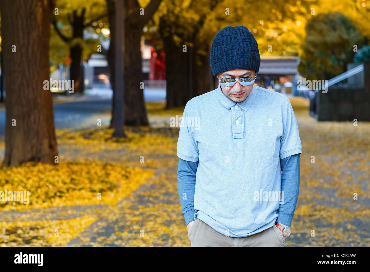 An asian man in a polo t-shirt walks on a street Stock Photo - Alamy