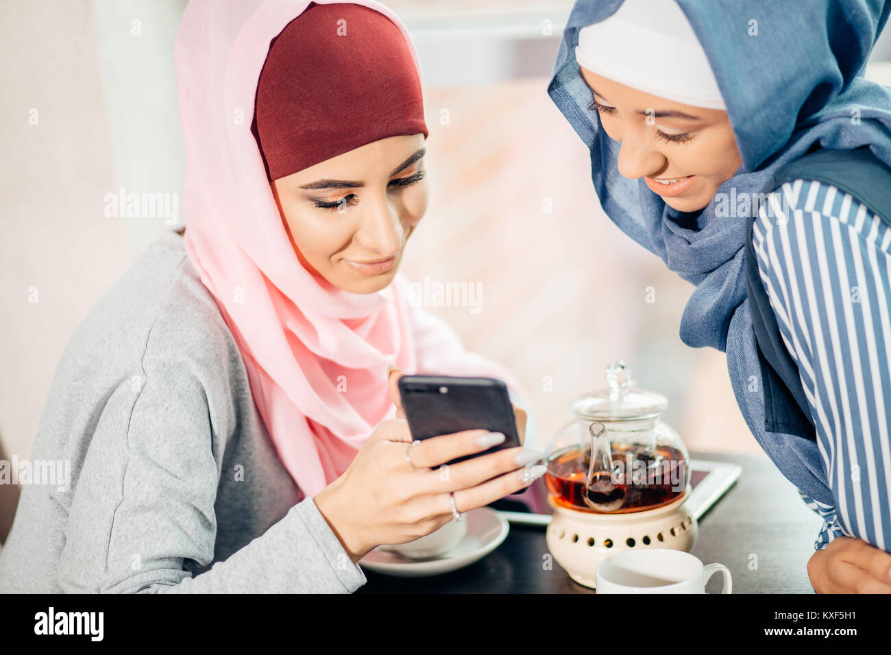 portrait of happy muslim woman using mobile phone while sitting on a ...