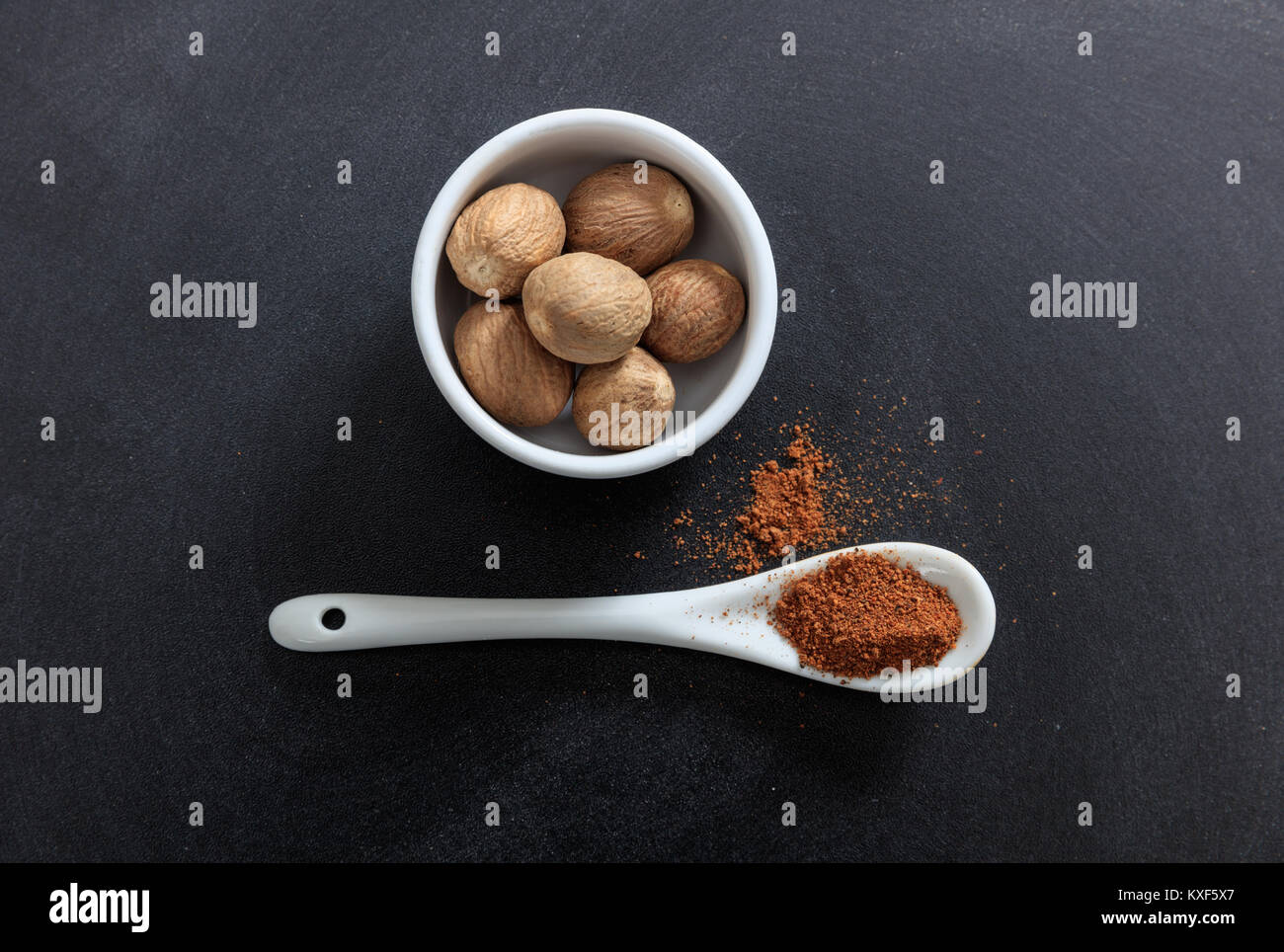 Nutmeg seeds and powder in porcelain bowl and spoon, black background ...