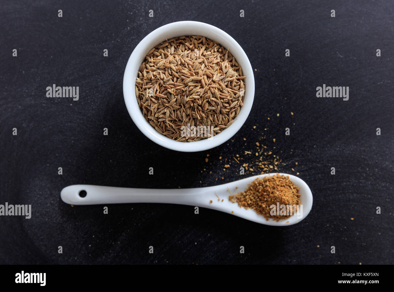 Cumin in porcelain bowl and spoon, black background Stock Photo - Alamy