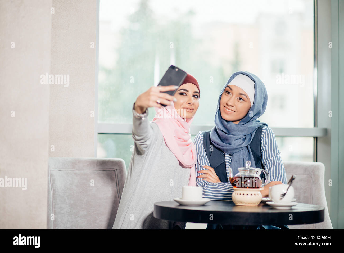 young beautiful muslim woman taking a self portrait with camera phone ...