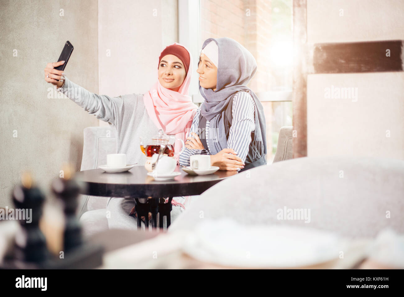 young beautiful muslim woman taking a self portrait with camera phone ...