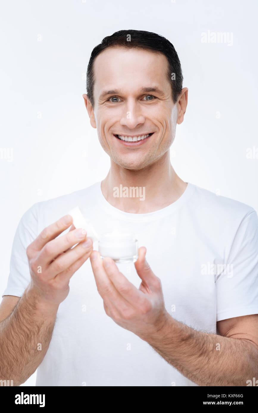 Delighted happy man using facial cream Stock Photo - Alamy