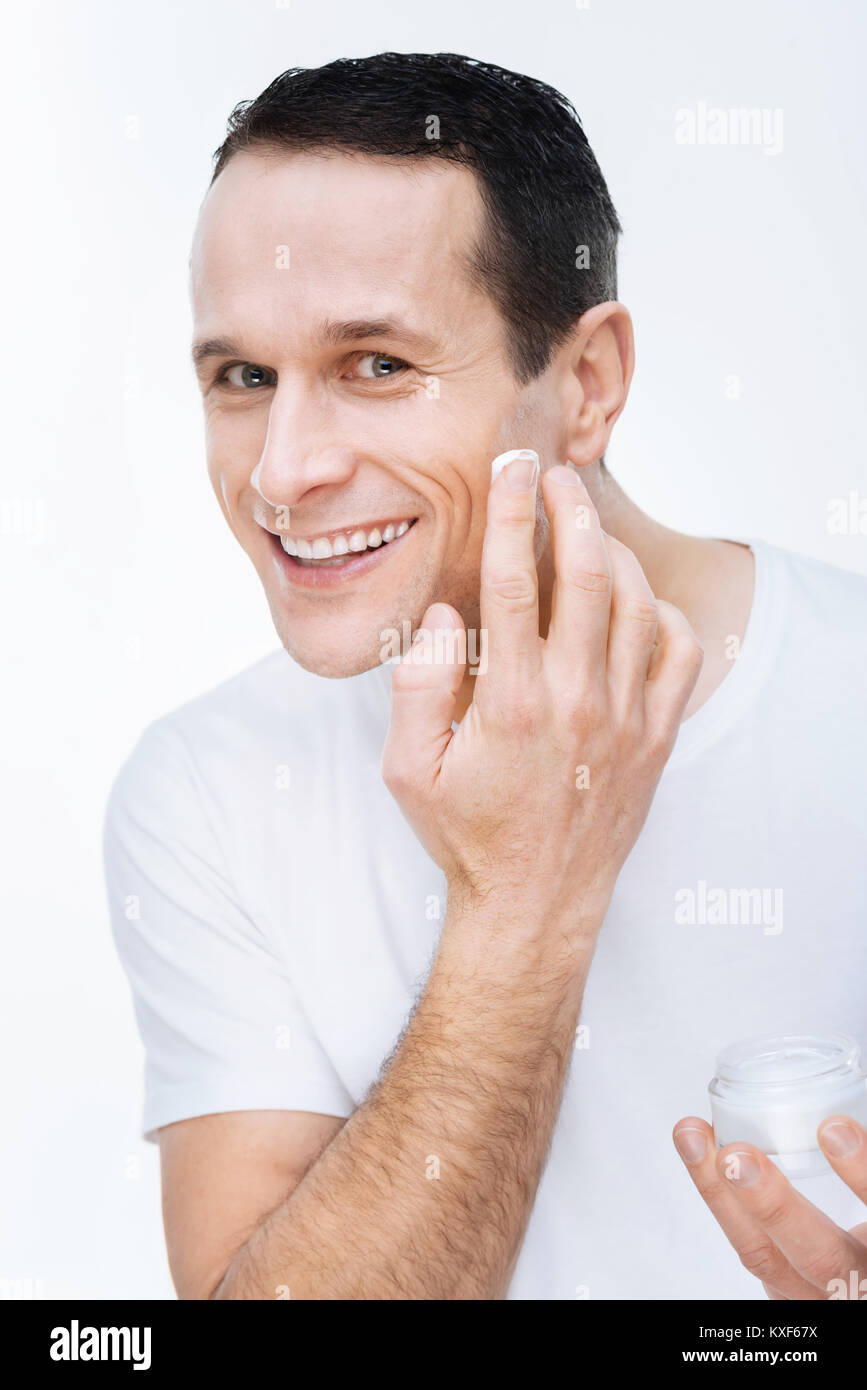 Delighted happy man applying moisturizing cream Stock Photo - Alamy