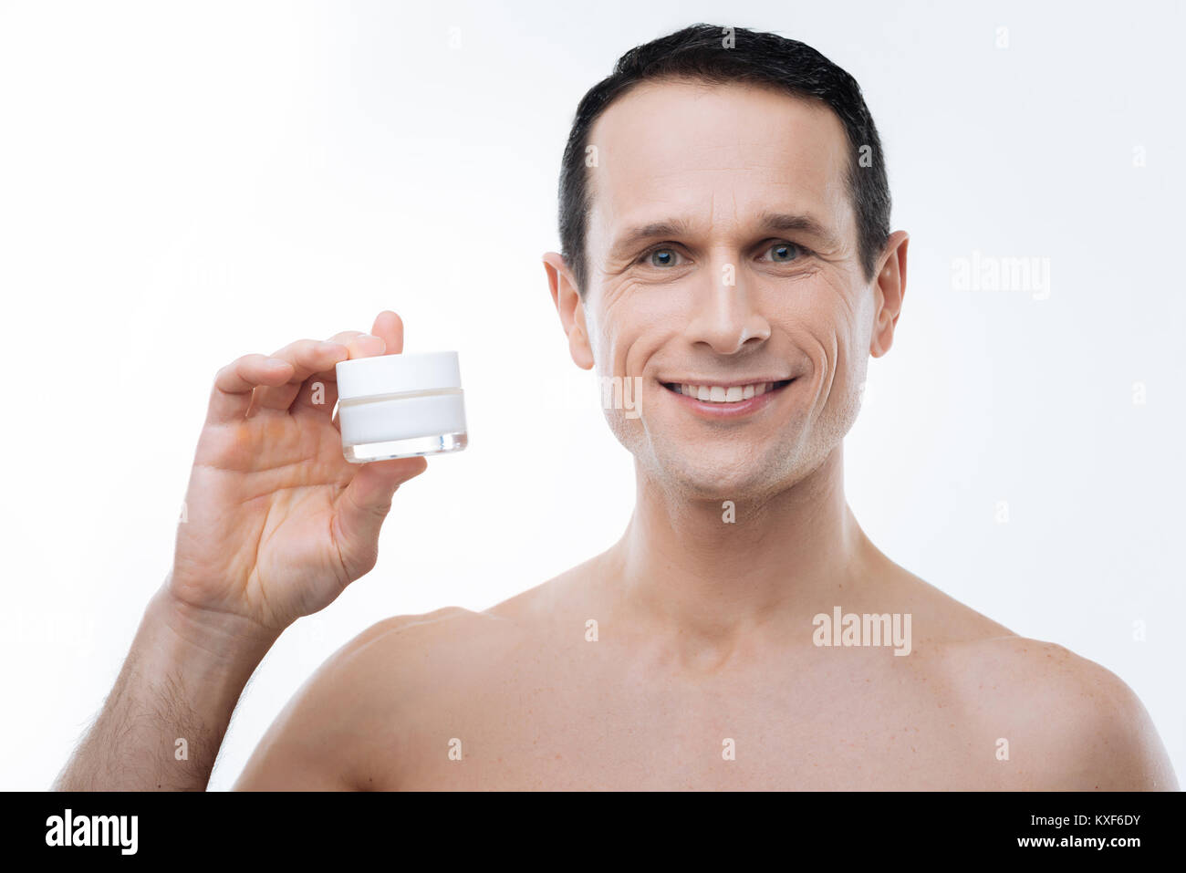 Delighted nice man using facial cosmetics Stock Photo - Alamy