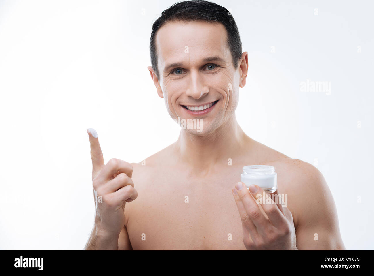 Joyful happy man being ready to use facial cream Stock Photo - Alamy