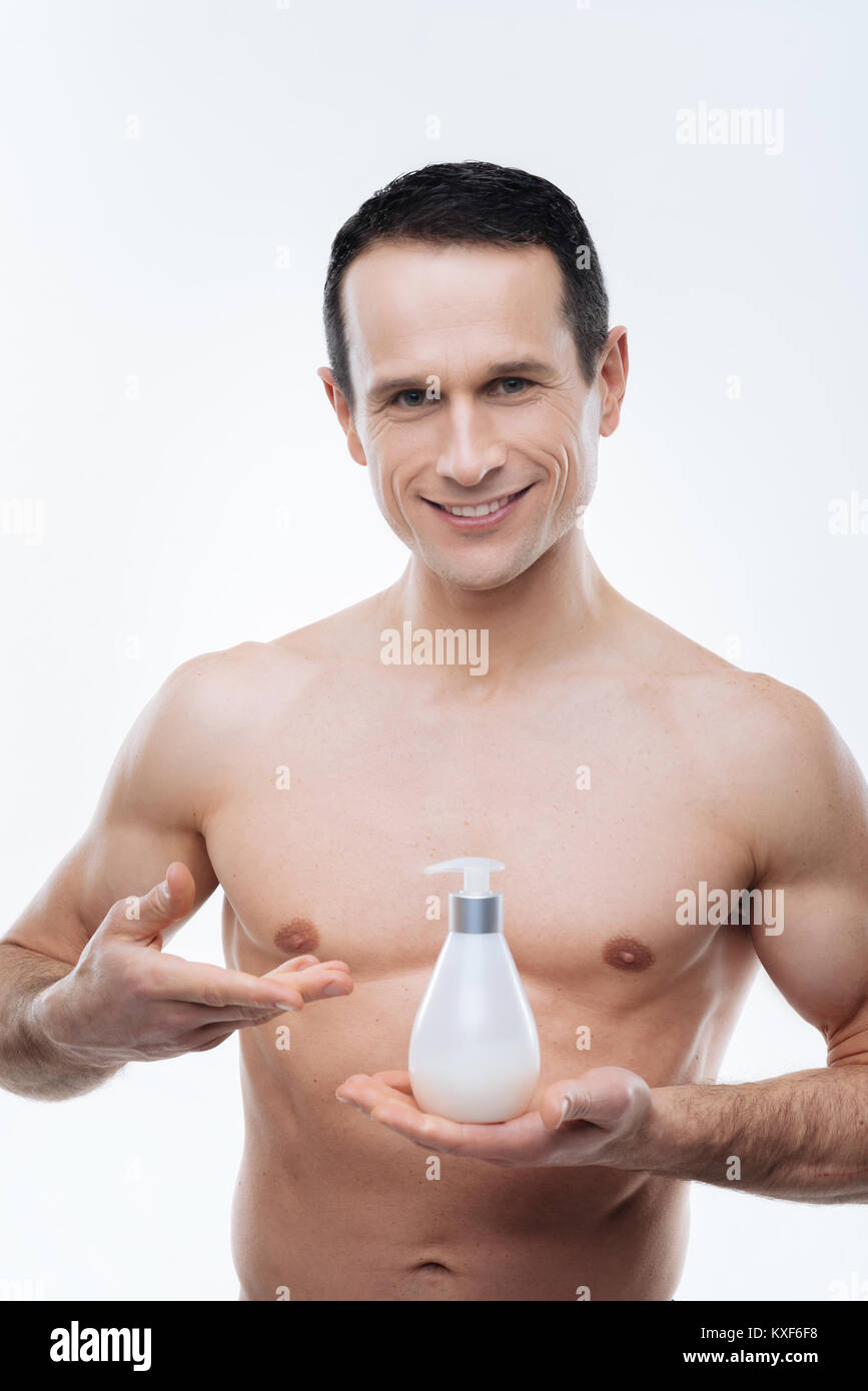 Nice delighted man presenting body lotion Stock Photo - Alamy