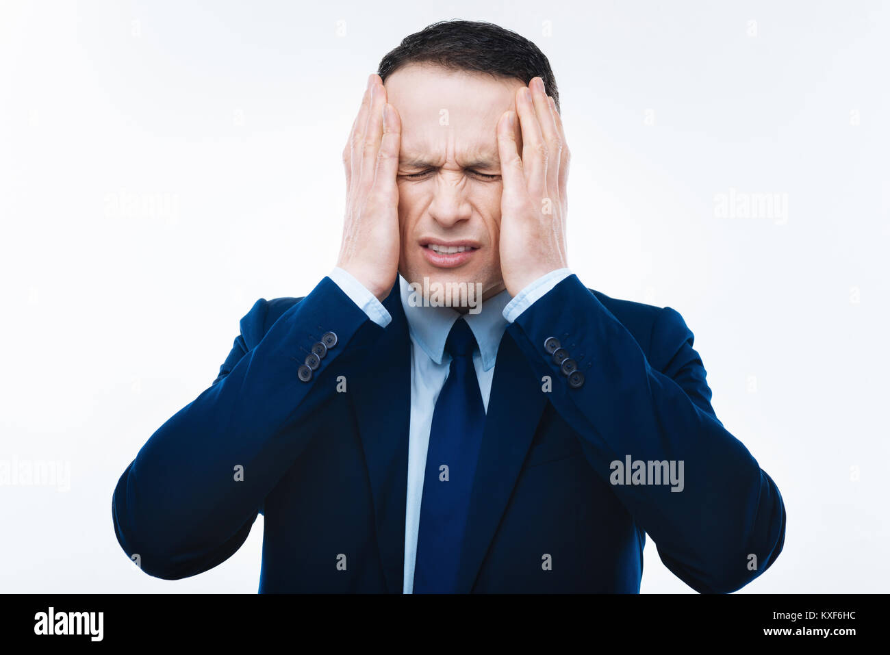 Unhappy serious businessman holding his head Stock Photo - Alamy