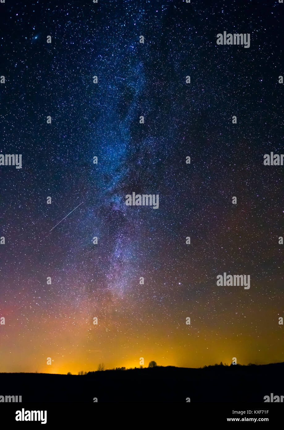 Night landscape with colorful milky way and yellow light in the horizon ...