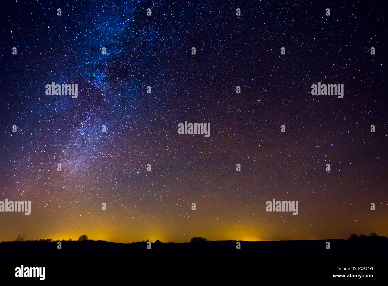 Night landscape with colorful milky way and yellow light in the horizon ...