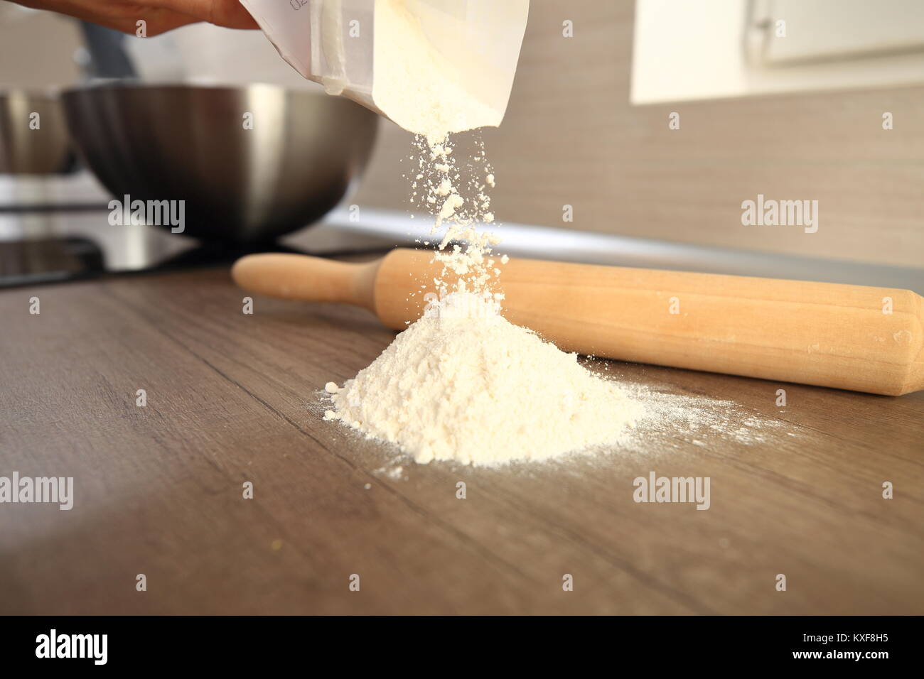 Pouring flour close-up. White flour is poured from a paper bag on a ...