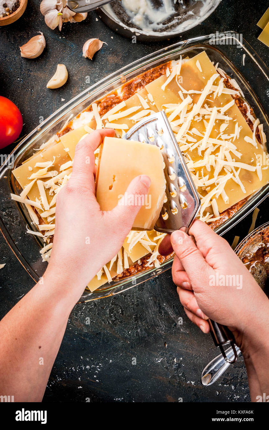 Woman cooking homemade classic lasagna bolognese, on dark blue table ...