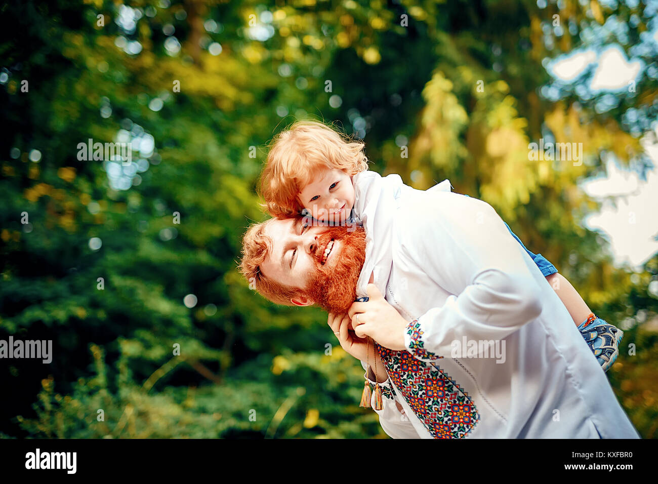 Red-heared father and red-heared son having fun in a park in a ...