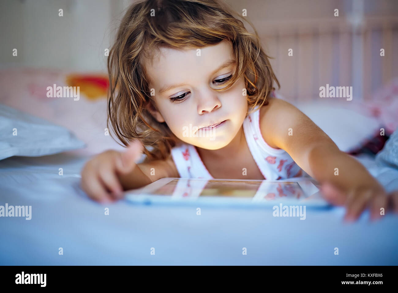little girl playing tablet at home on a bed Stock Photo - Alamy