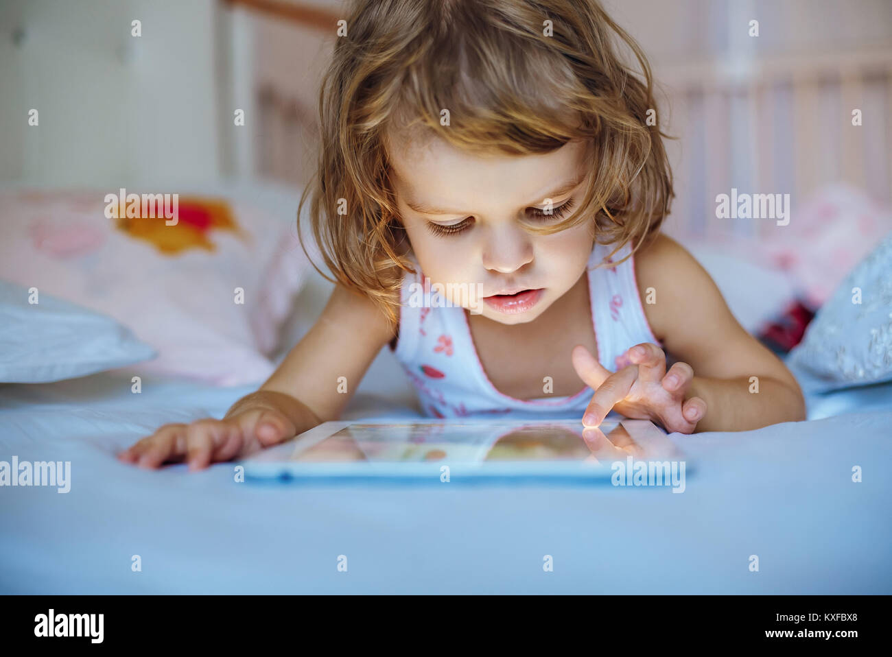 little girl playing tablet at home on a bed Stock Photo - Alamy