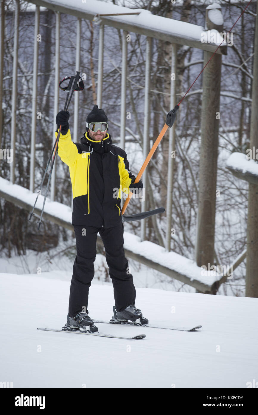 Happy smiling male skier using t bar ski drag lift and greeting waving ...