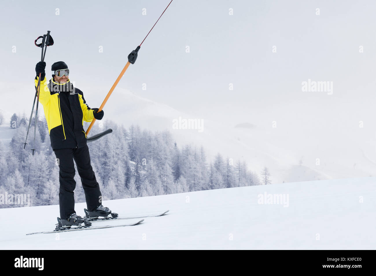 Happy smiling male skier using t bar ski drag lift and greeting waving ...