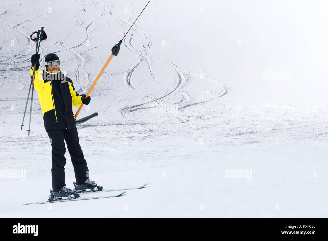 Happy smiling male skier using t bar ski drag lift and greeting waving ...