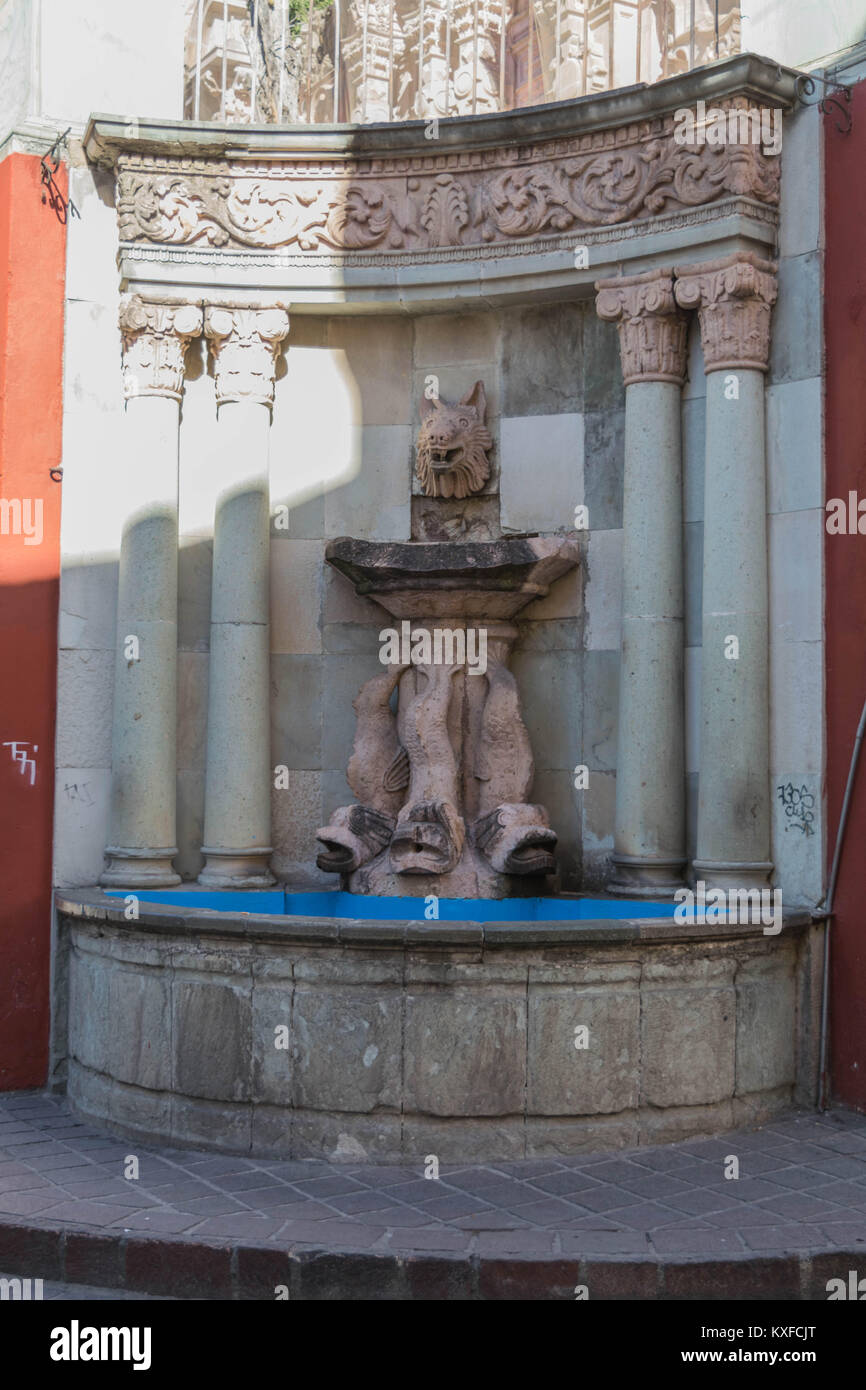 Marble stone water fountain, with a wolfs head at the top and fish ...
