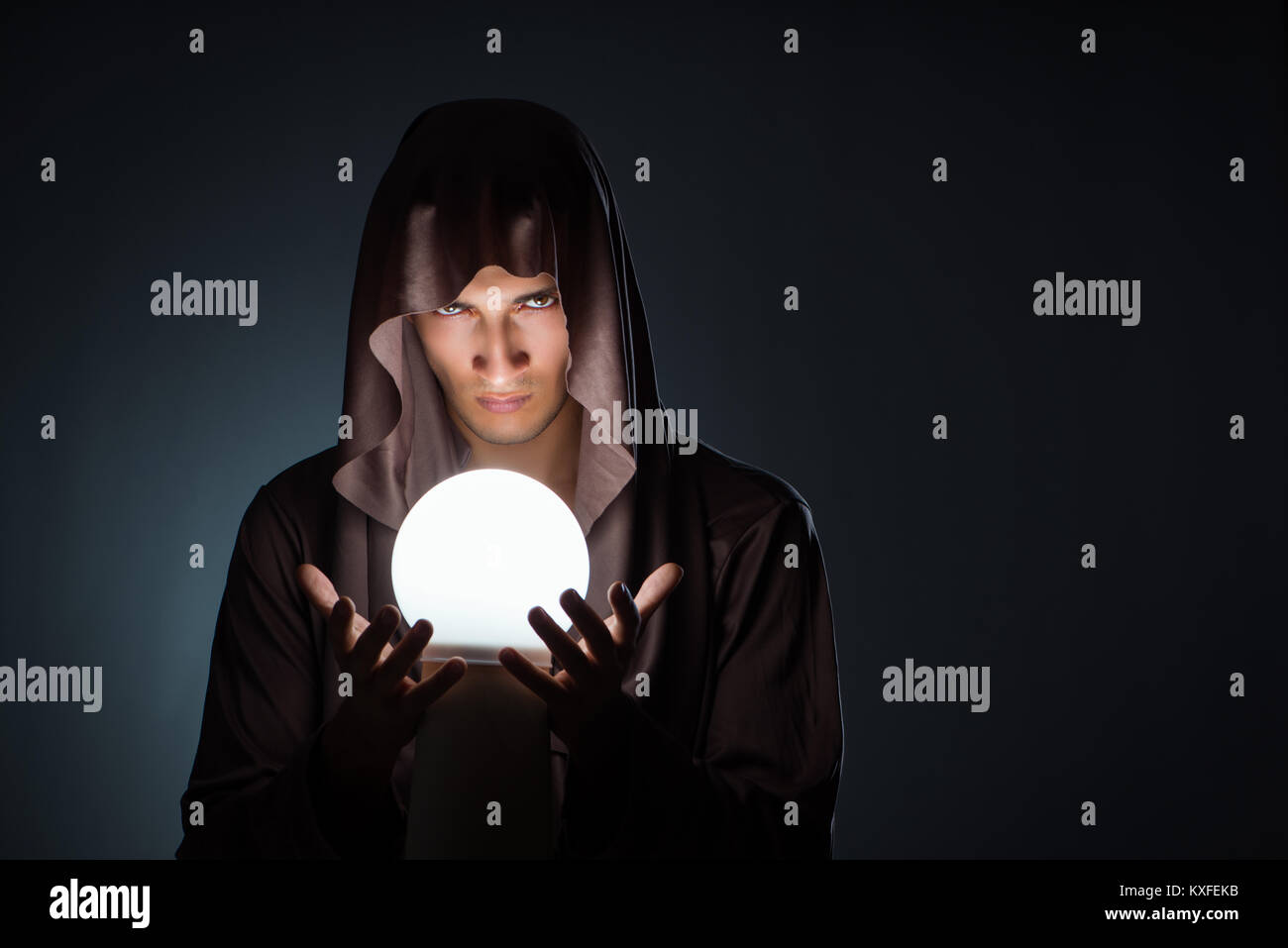 Young wizard with crystal ball in dark room Stock Photo - Alamy