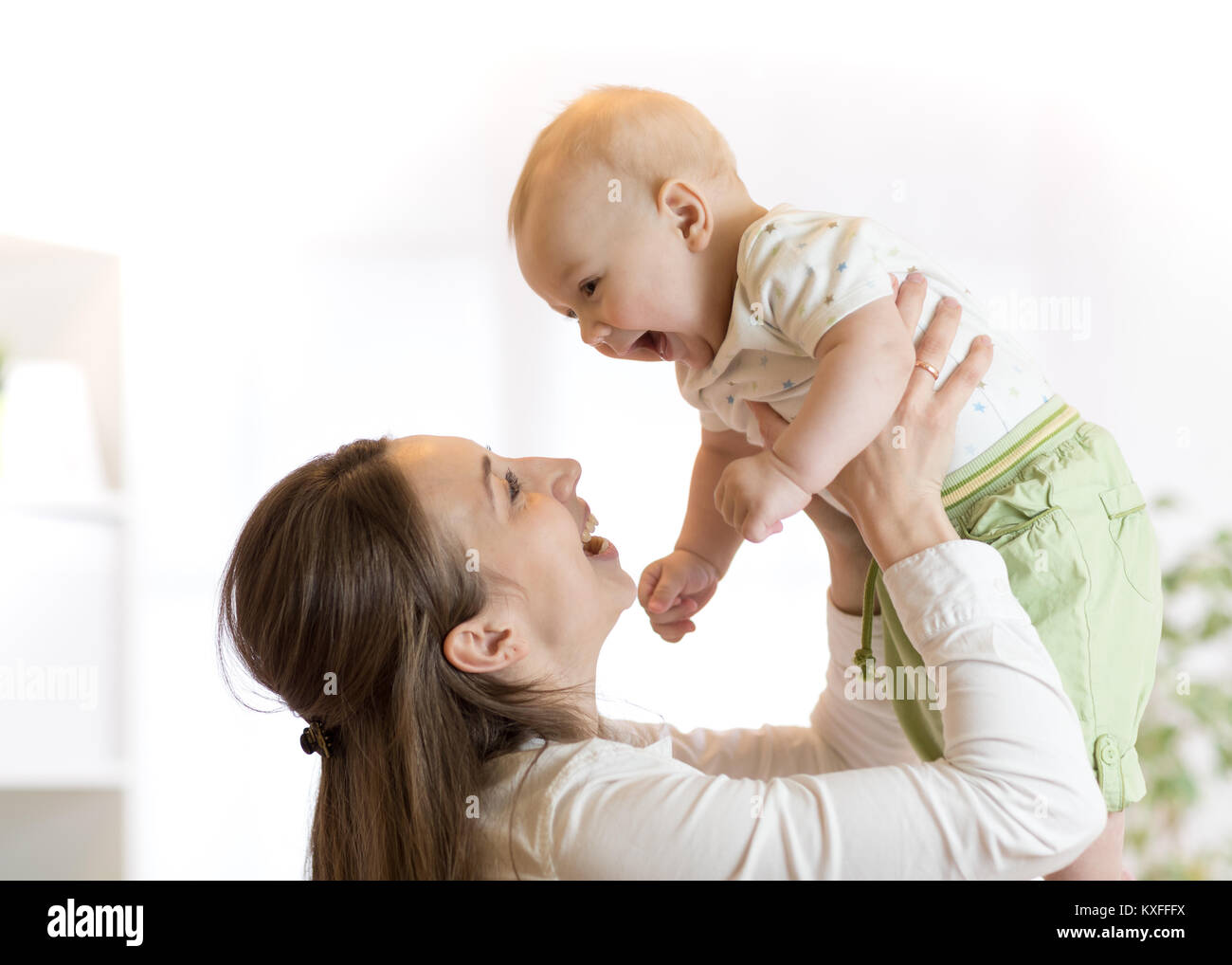 Happy mother raising baby and playing with him Stock Photo - Alamy