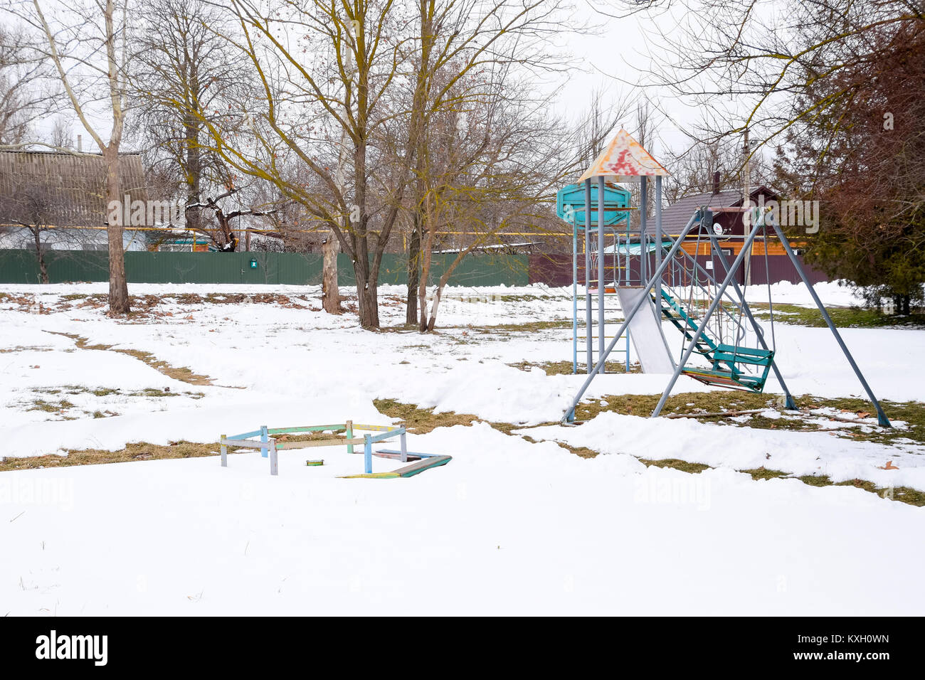 Children's playground in winter under snow. Swing, carousel and slide ...