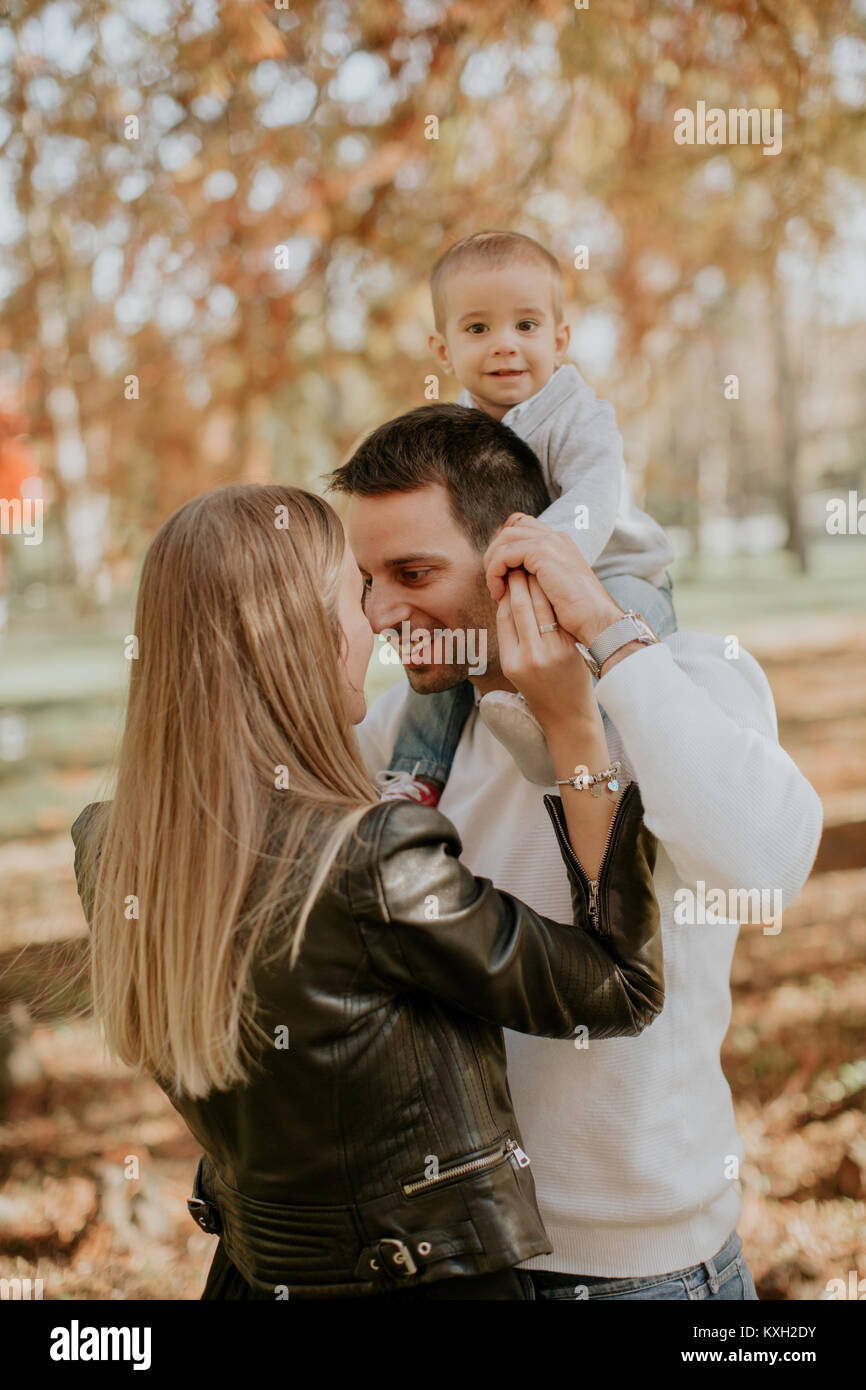 Happy young parents have fun with baby boy in autumn park Stock Photo ...
