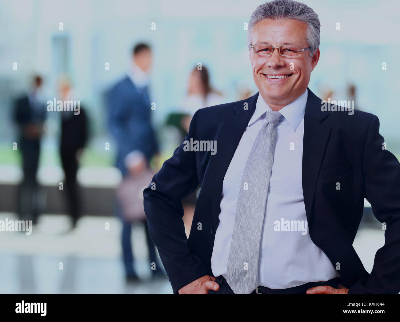 Successful business man standing with his staff in background at office ...