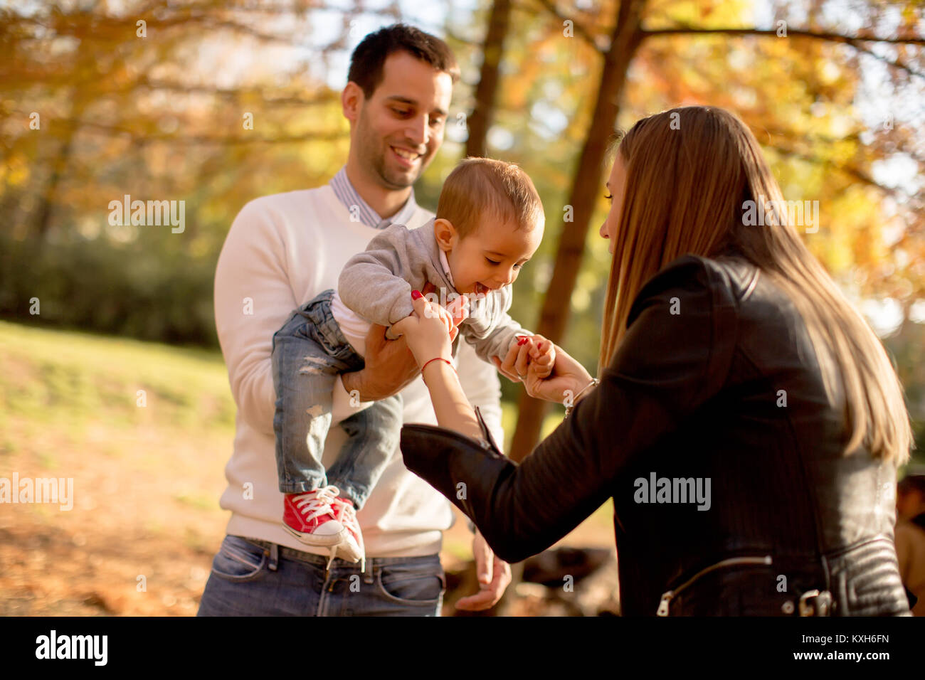 Happy young parents have fun with baby boy in autumn park Stock Photo ...
