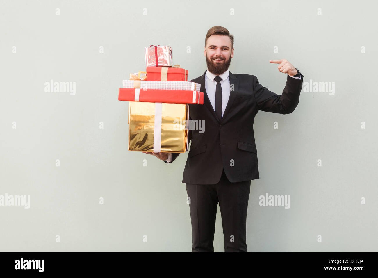 Handsome businessman pointing finger gift boxes and looking at camera ...