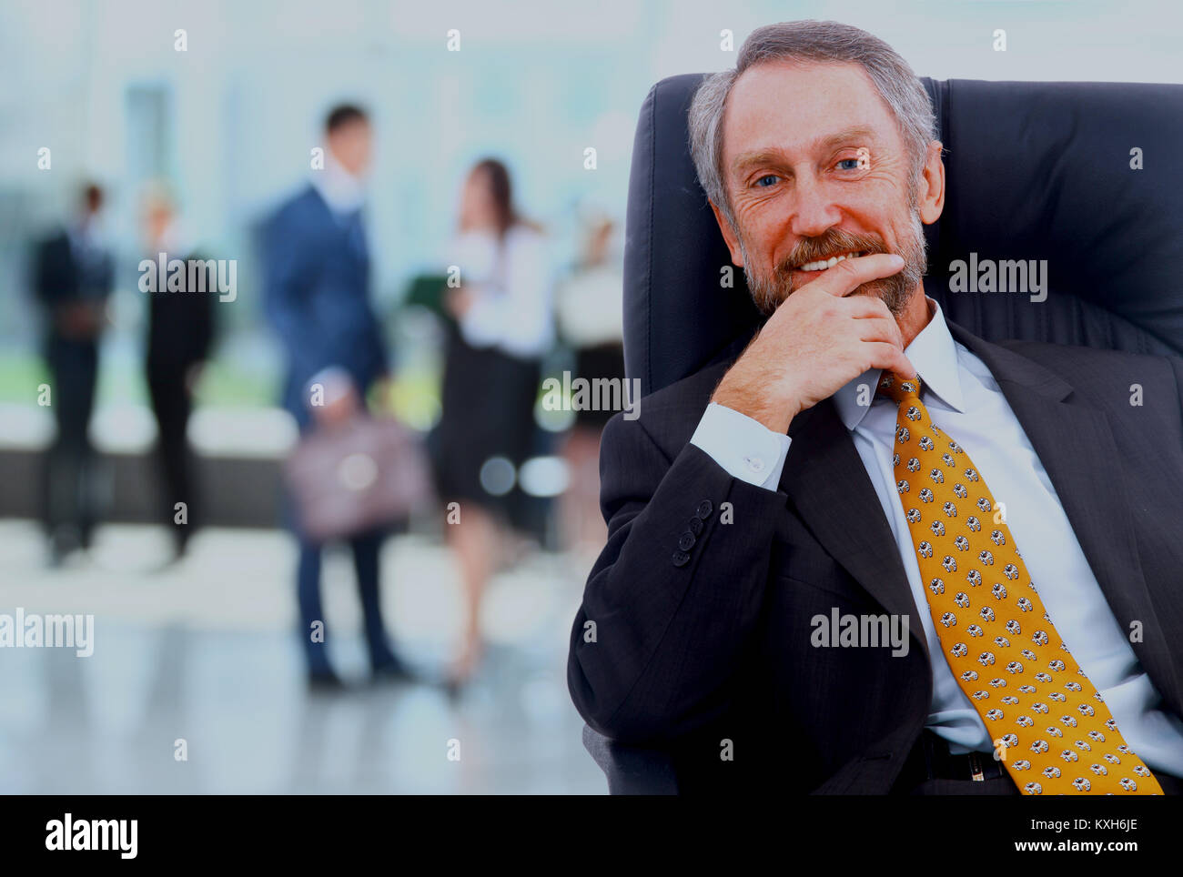 Successful business man standing with his staff in background at office ...