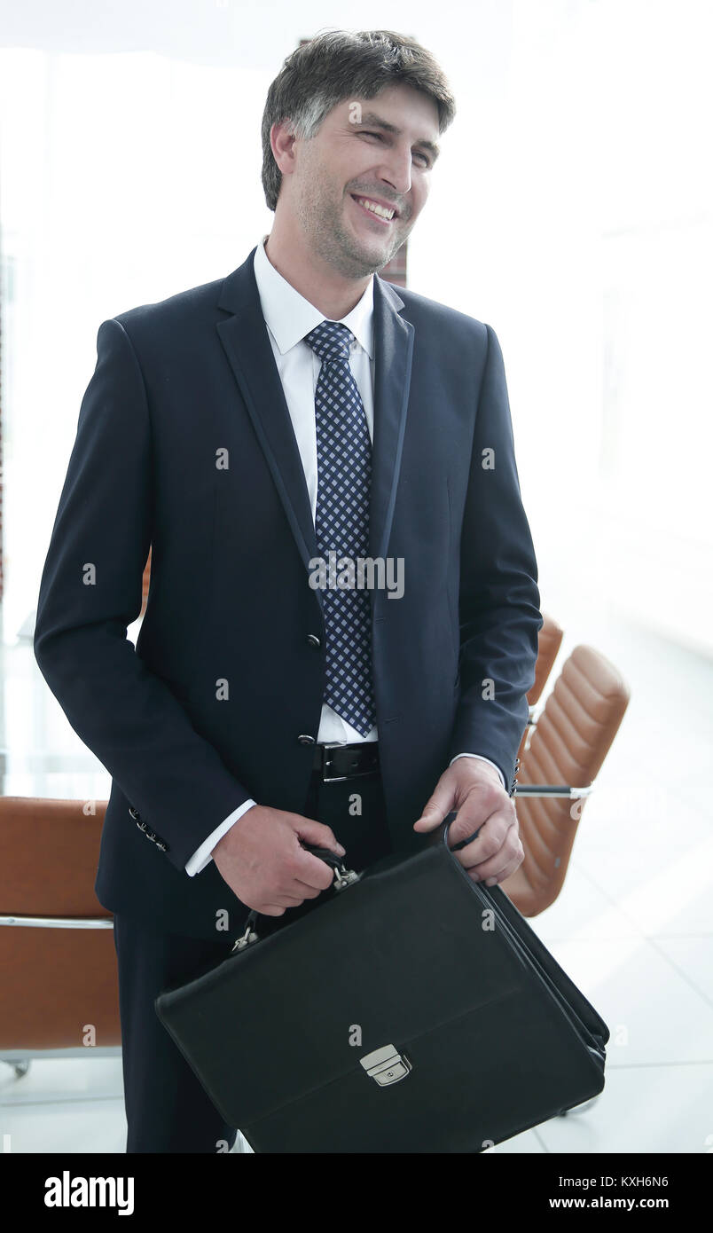 Business man with briefcase standing on office background Stock Photo ...