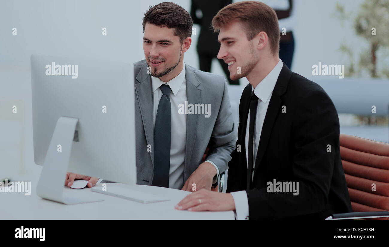 Smiling business men showing something on computer as colleague looking ...